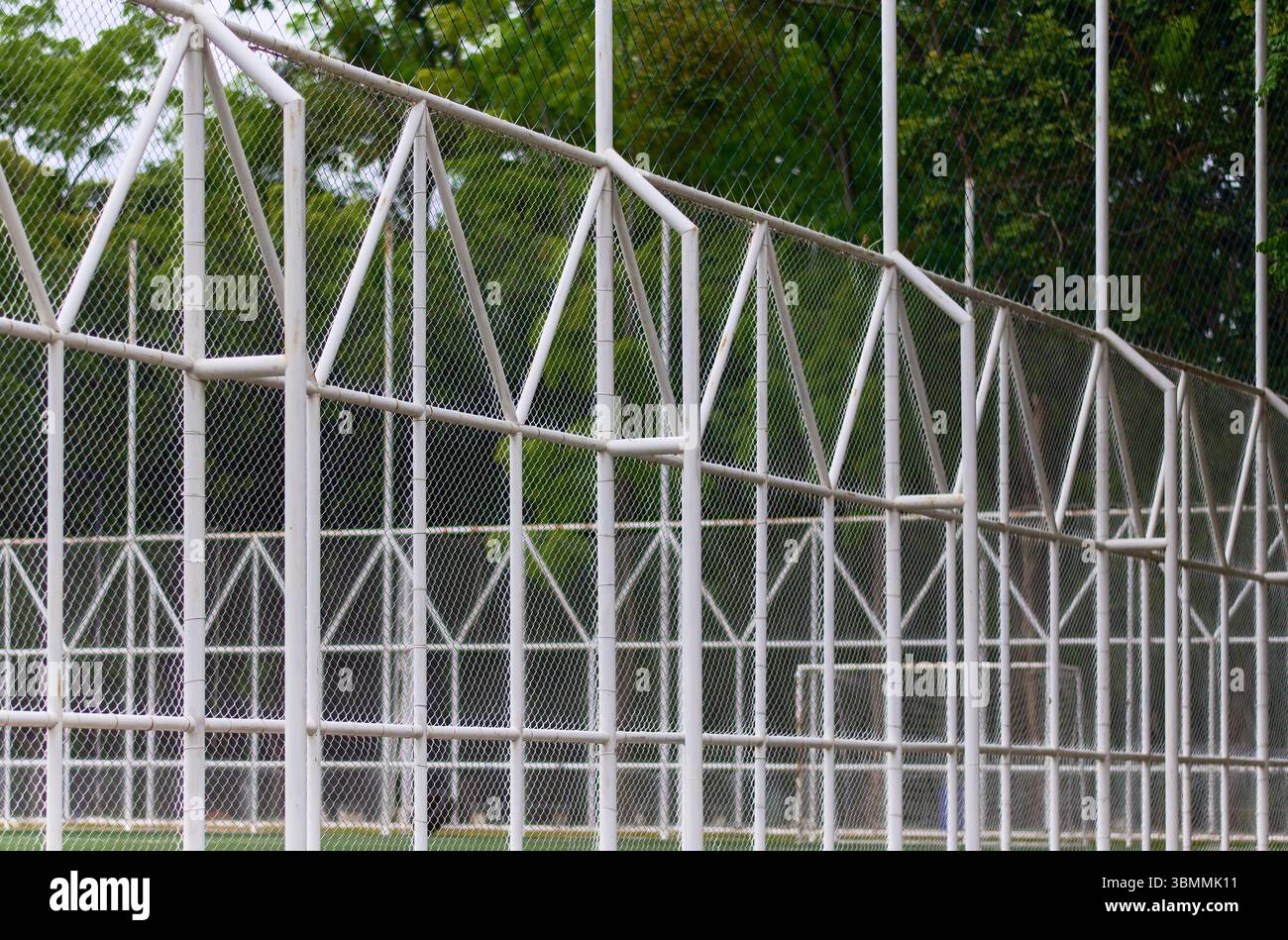 A modern boundary structure around a sports or training field, made from metal mesh and ...