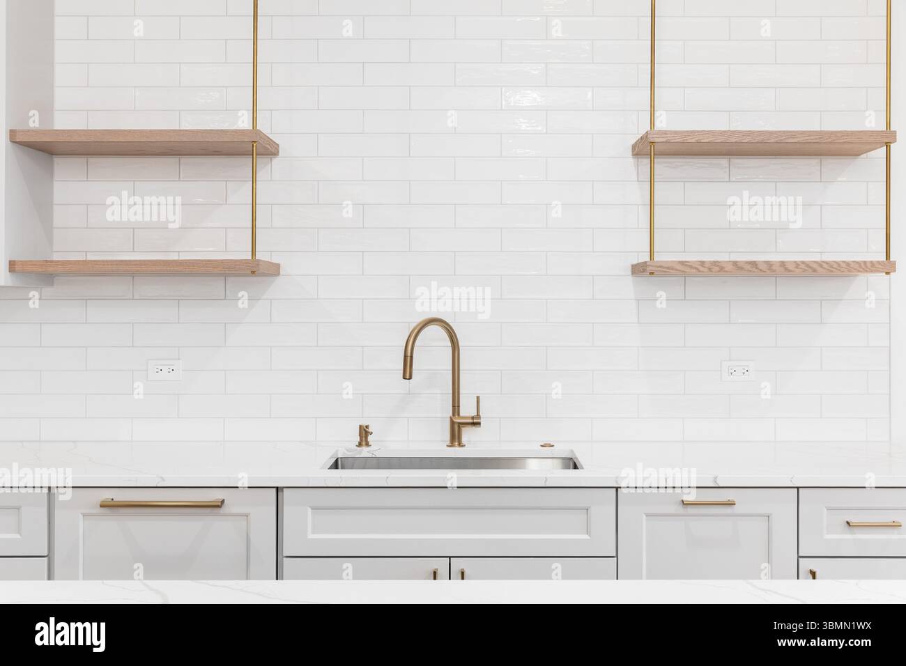 A kitchen faucet detail with a gold faucet and hardware, white subway ...