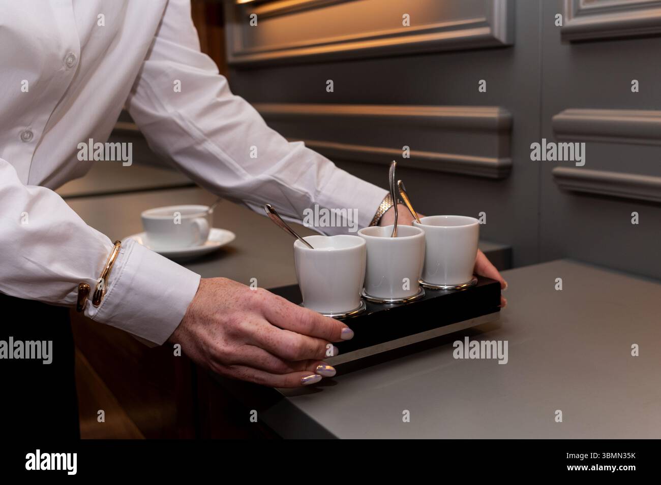 Waiter in white shirt placing containers with sugar on table. Waiter's ...