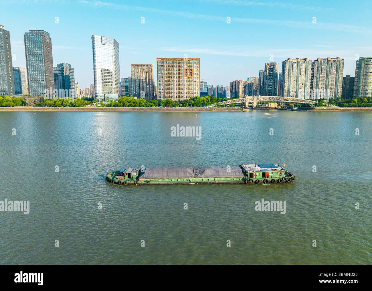Aerial view of barge navigates river in urban setting with modern ...