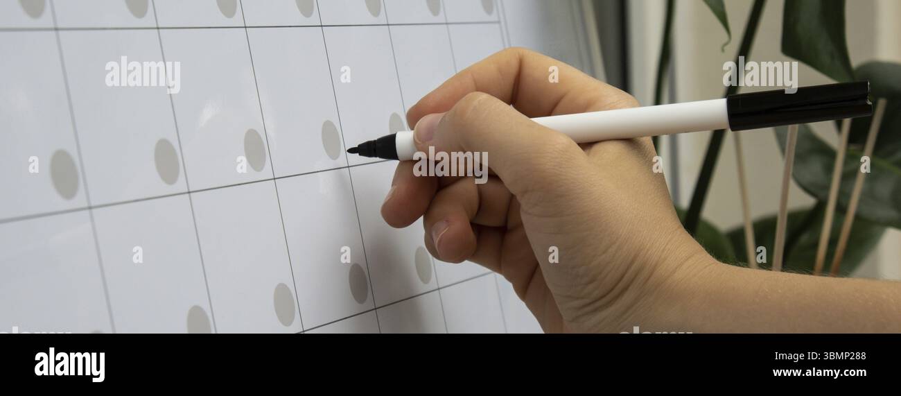 Female hand writing with marker on Monthly PLANNER. Magnetic board with ...