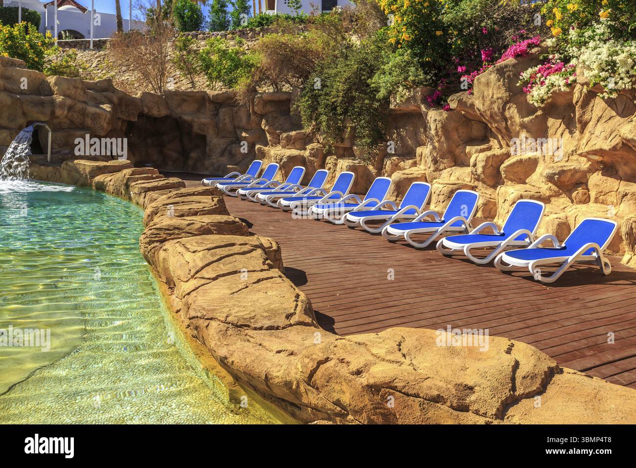 Swimming pool with artificial waterfall and sun loungers, luxury ...