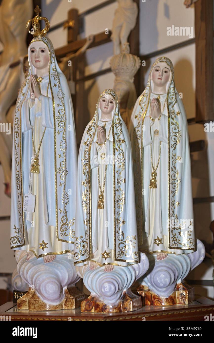 Three statues of Our Lady of Fatima praying on clouds in a souvenir ...