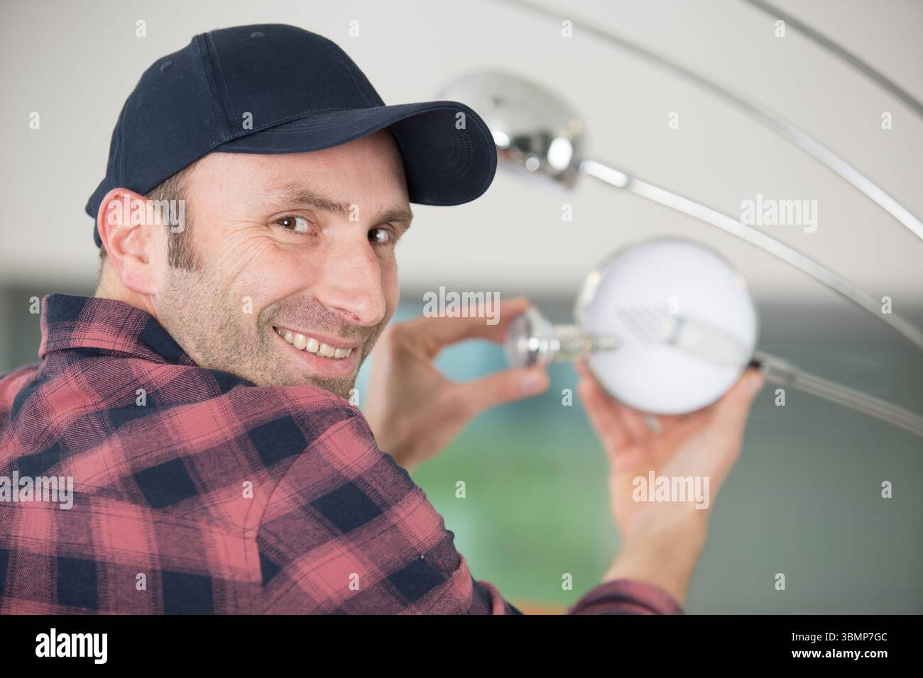 happy builder fitting a light bulb Stock Photo - Alamy