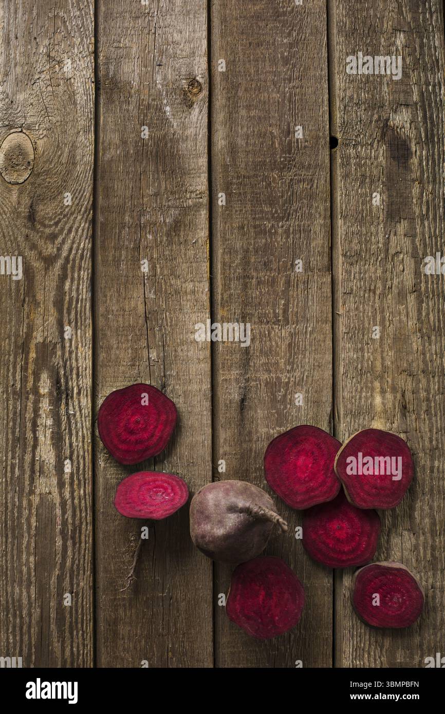 A sliced beetroot on a slate and wooden counter top background forming ...