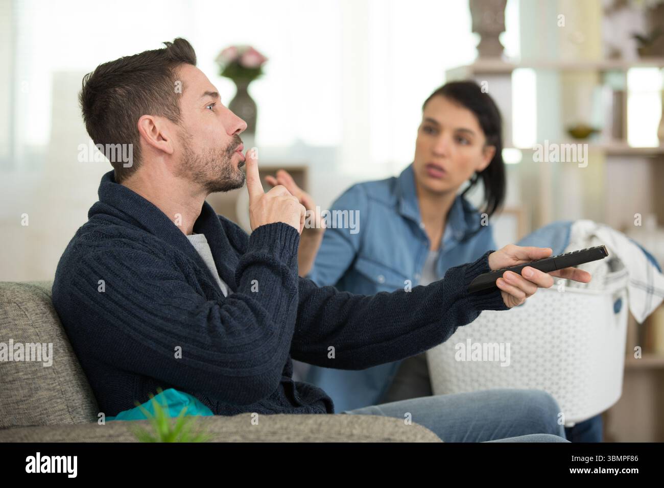 man hushing wife while watching television Stock Photo - Alamy