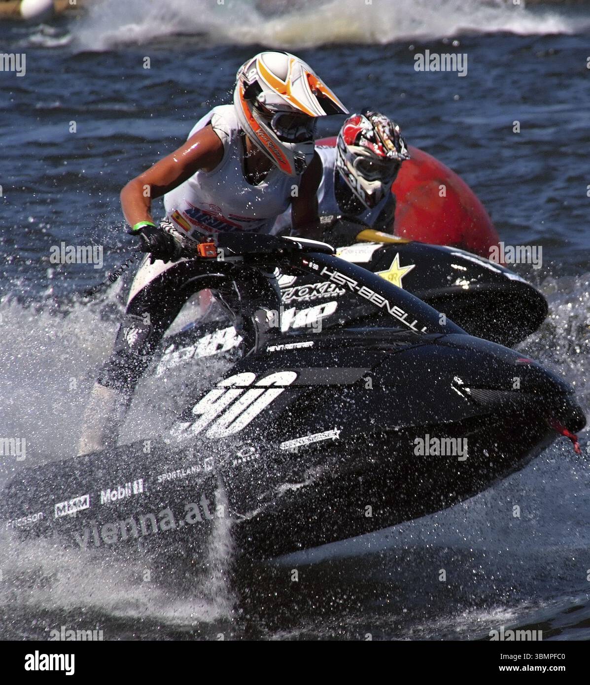 Female pilot competing in a jet ski race, creating a splash of water ...