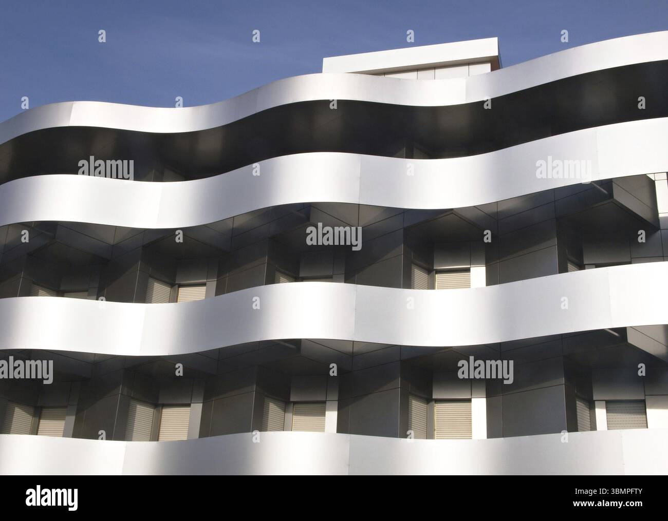 Wavy facade of a modern building with balconies and closed shutters ...