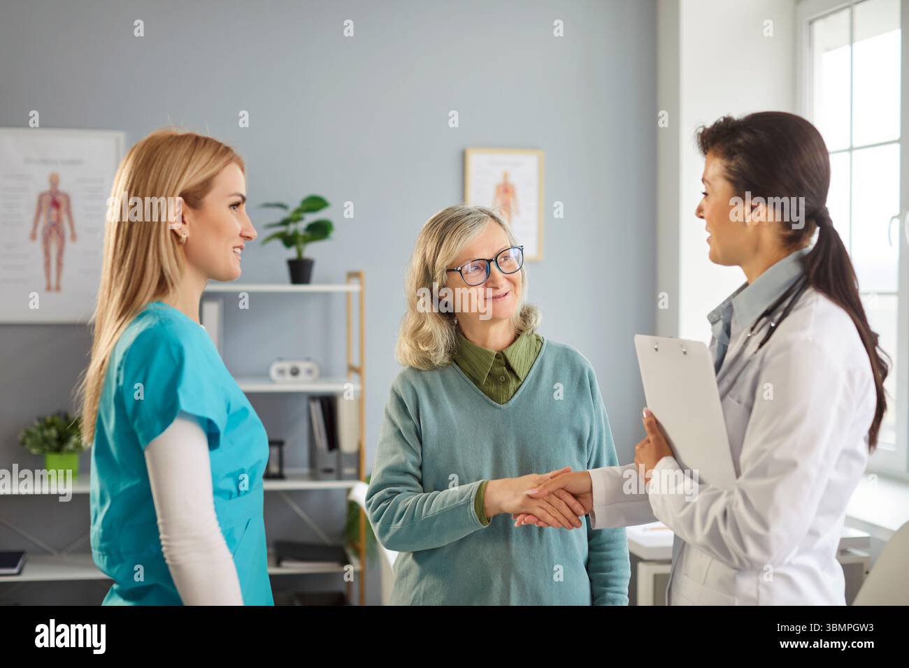 Doctor And Nurse Shaking Hands With Elderly Patient During Hospital ...