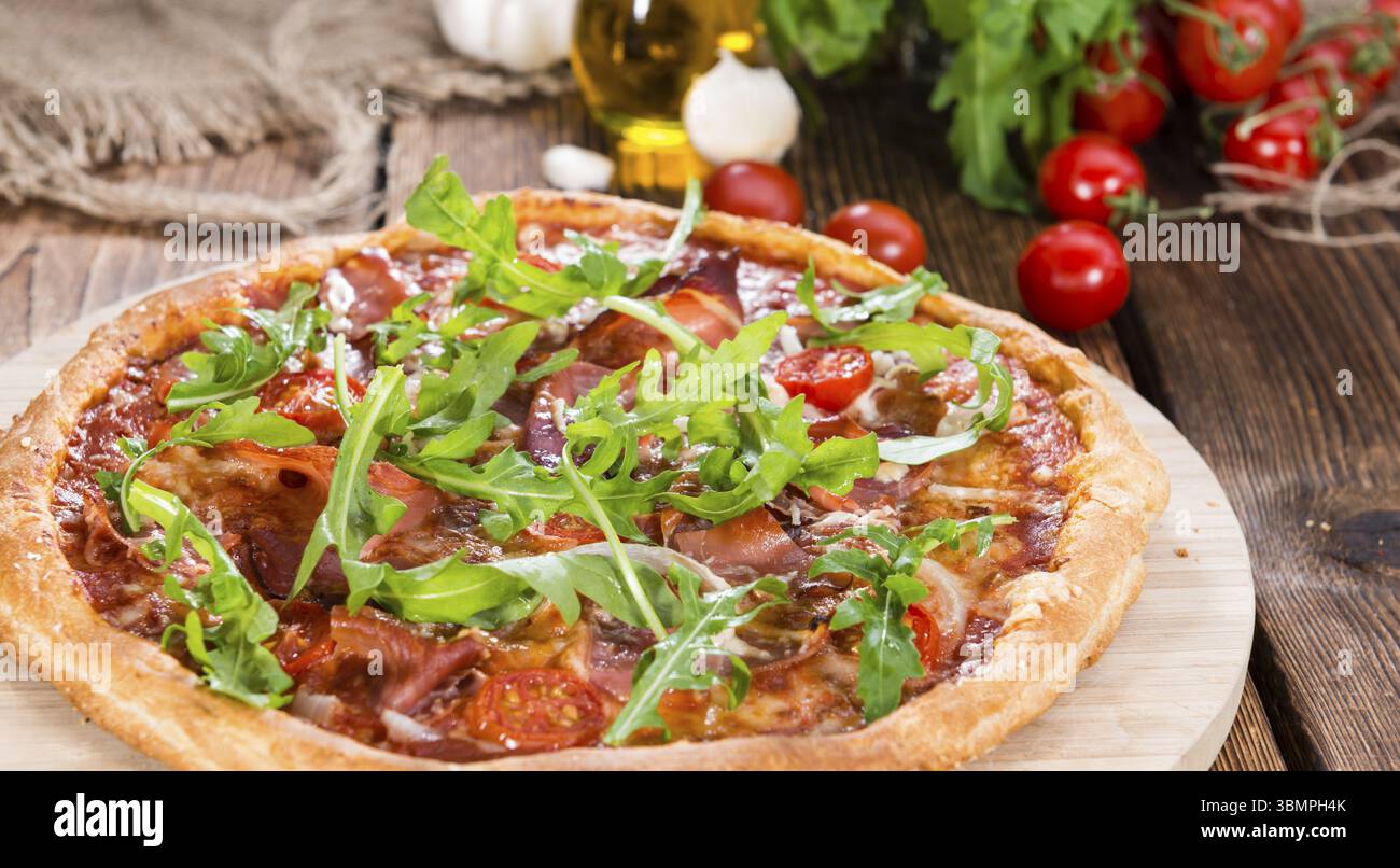 Ham Pizza with rocket and fresh tomatoes on rustic wooden background ...