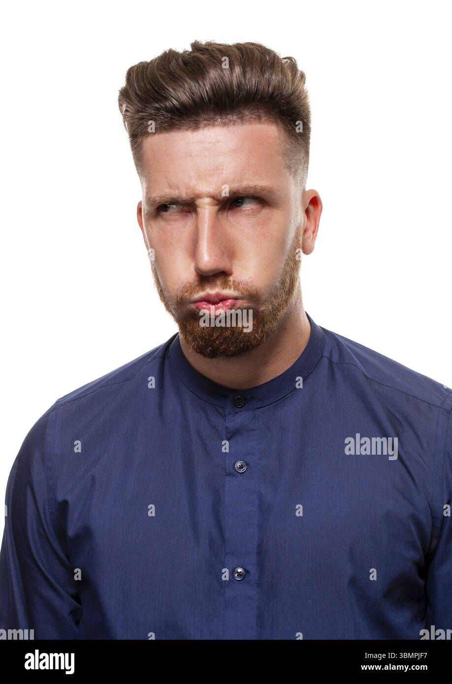 Attractive young bearded man wearing blue shirt is puffing out his ...