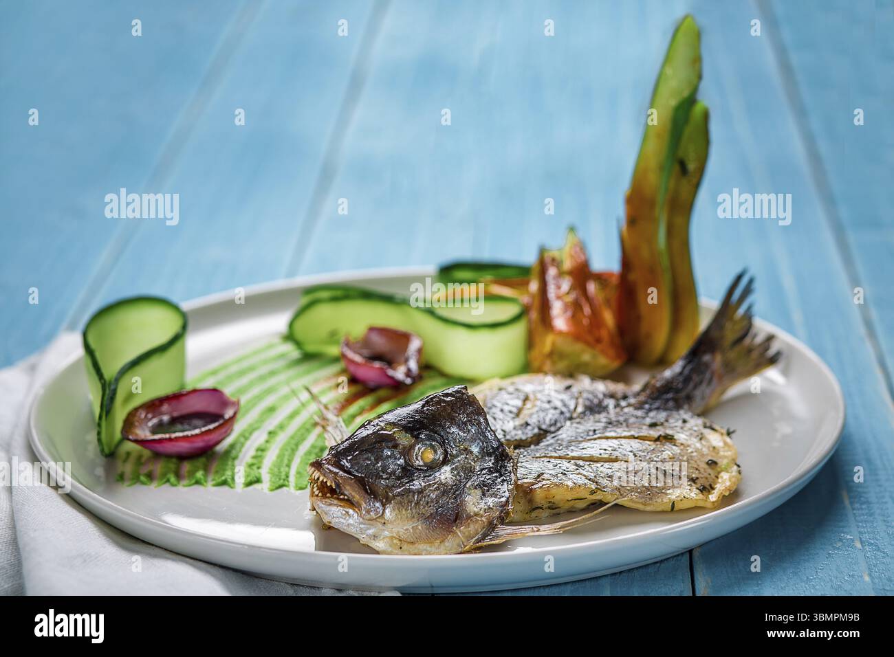 Fried fish dorado, decorated with cucumbers and onions. The original ...
