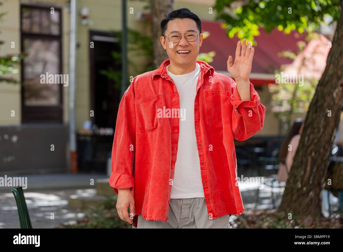 Hello. Asian middle-aged man smiling friendly at camera, waving hands ...