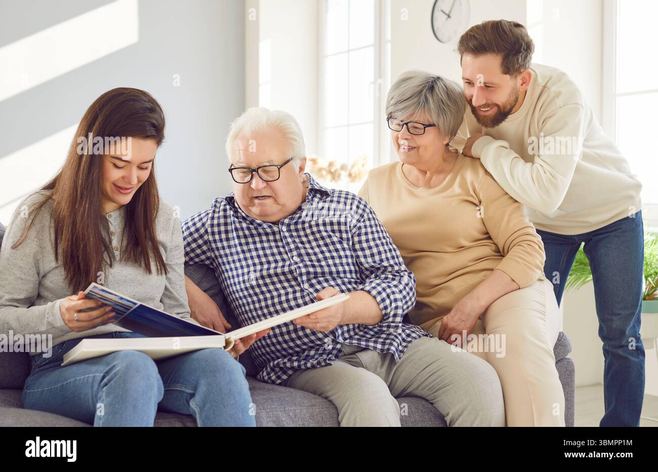 Elderly Parents And Grown Children Looking At Family Photo Album Stock ...