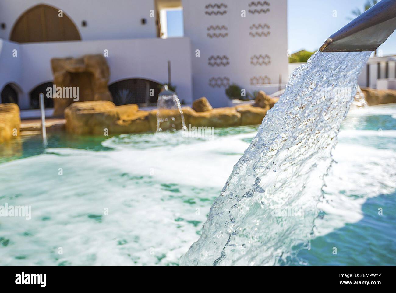 Stream of water out of artificial waterfall in outdoor pool at the ...
