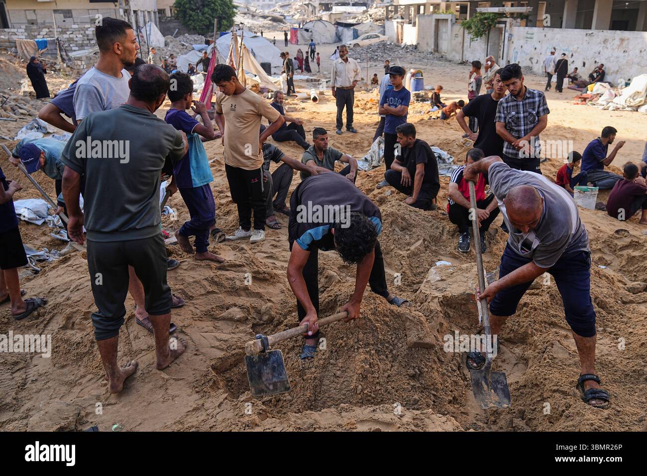 Palestinians dig through sand looking for belongings after an Israeli ...