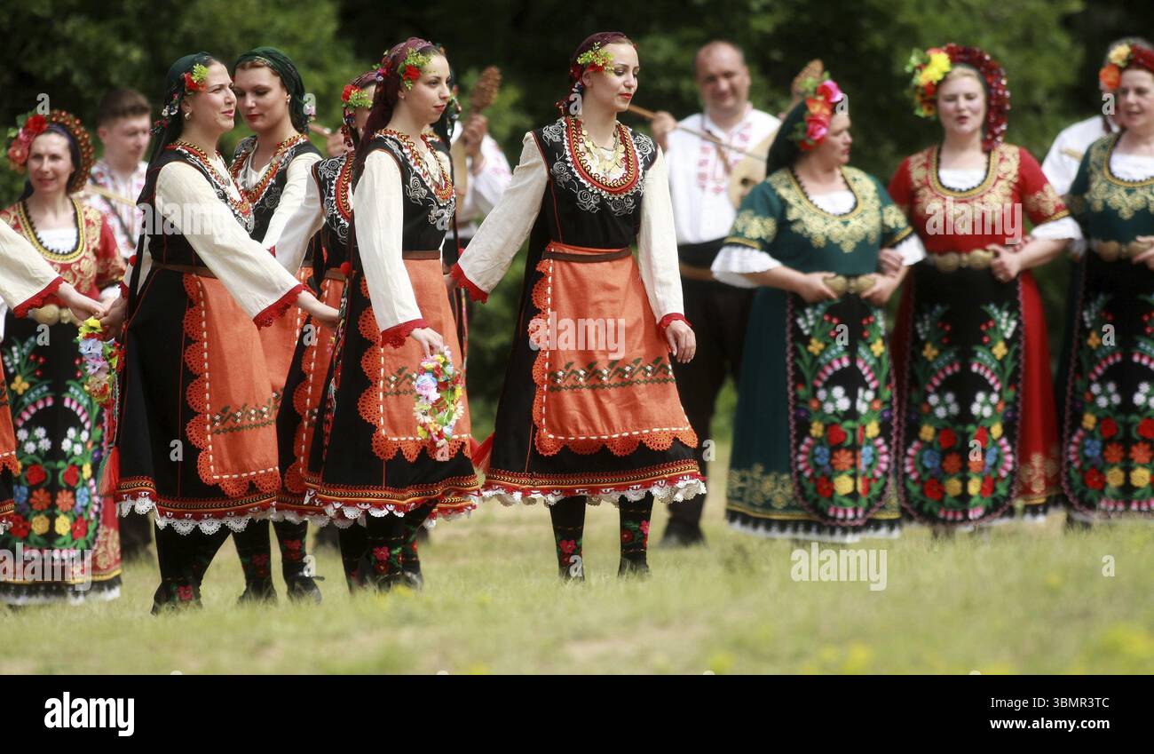 People in traditional costumes dance bulgarian horo a meadow near the ...