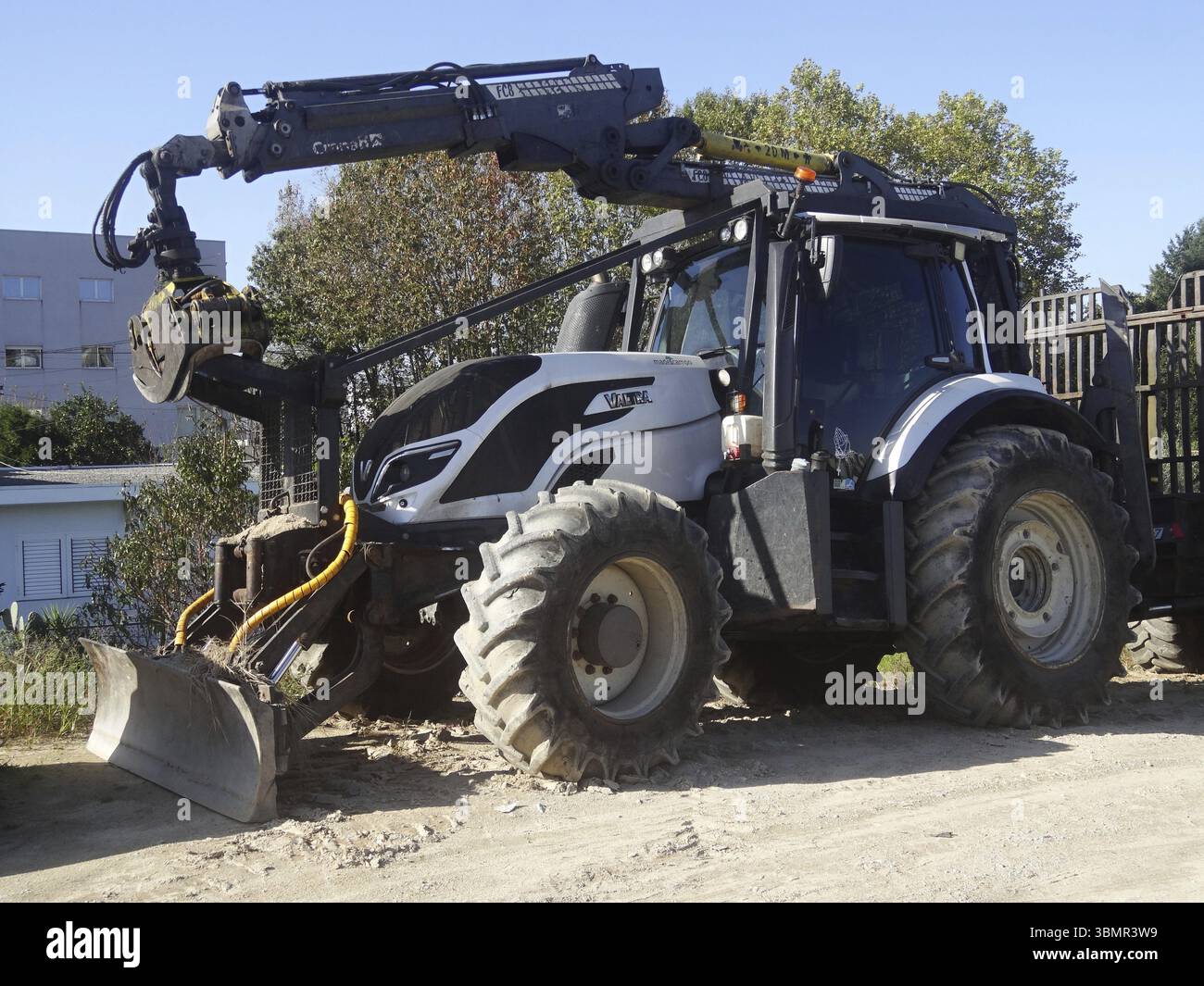 Forestry tractor parked on a construction site, equipped with crane and ...