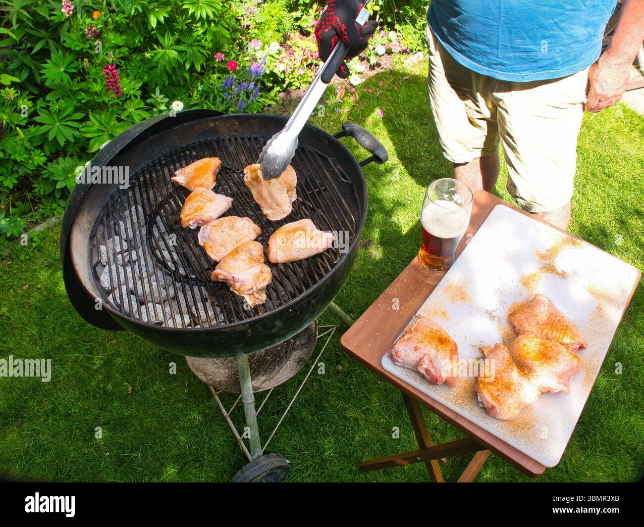Man enjoying a sunny day while putting chicken thighs on his backyard ...