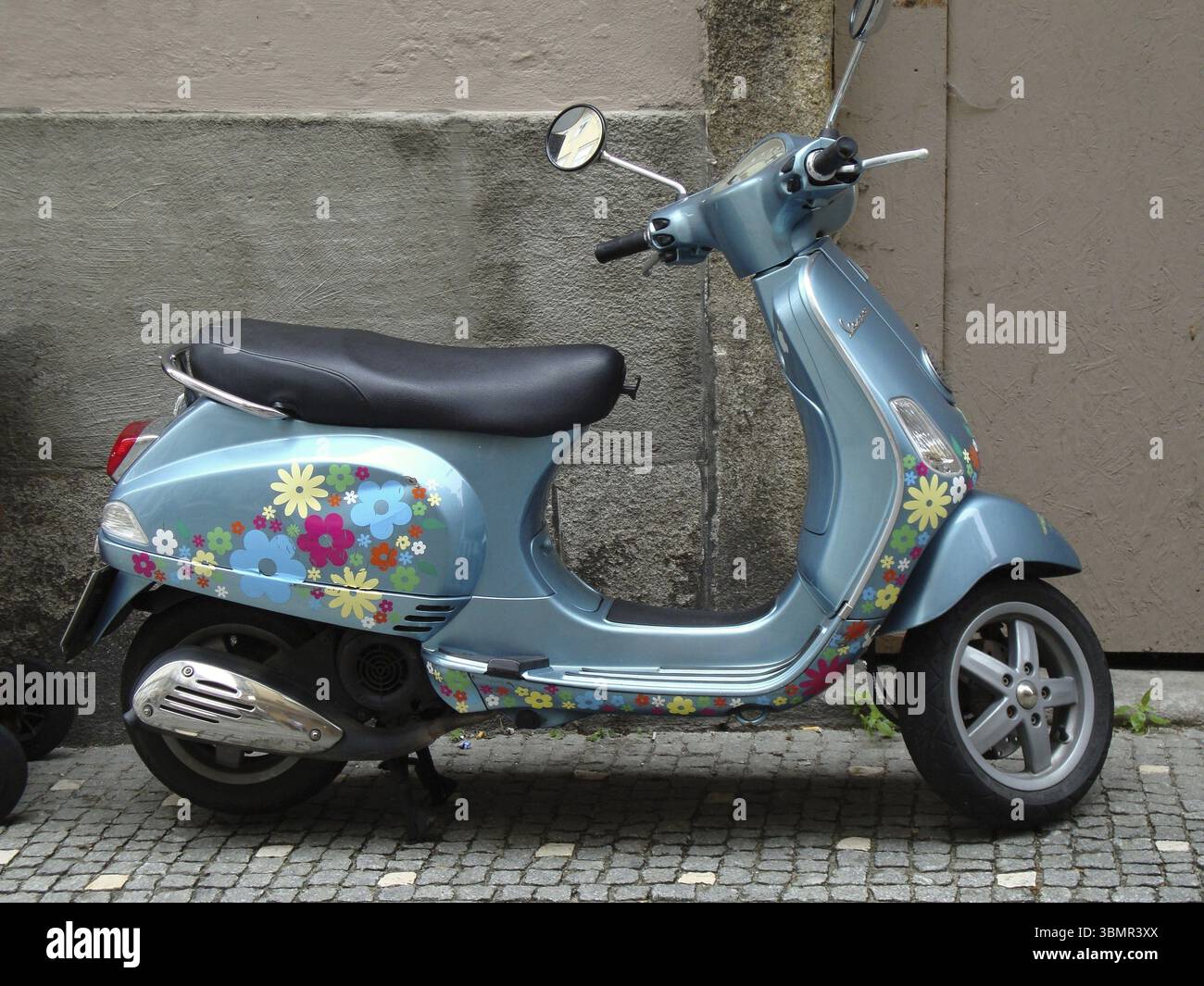 Light blue Vespa with colorful flower stickers parked on a cobblestone ...