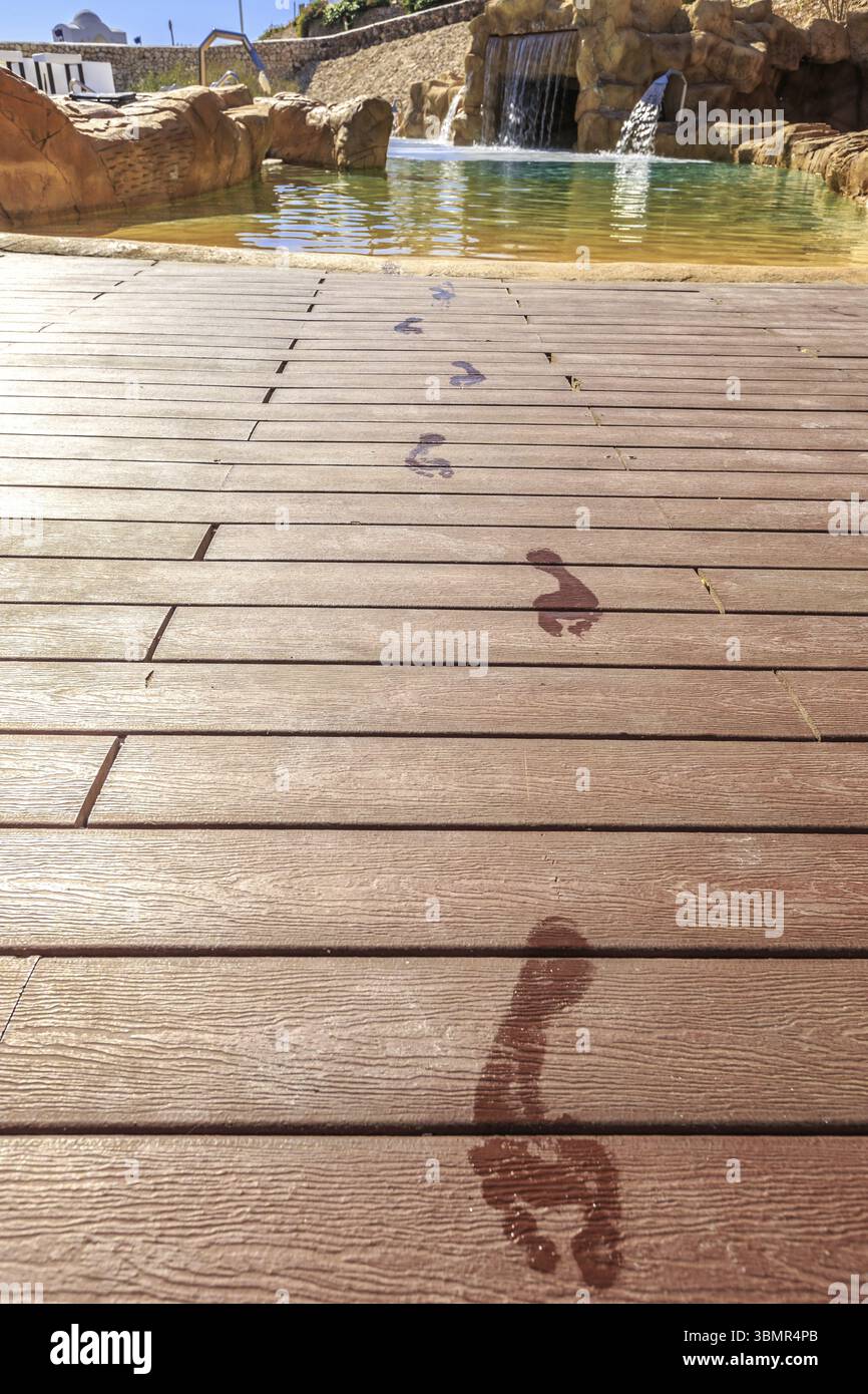 Closeup footprints on the wooden floor behind it swimming pool with ...