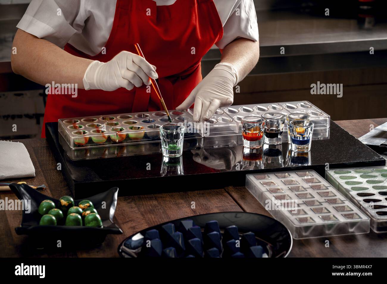 Close-up woman a confectioner in red uniform and white gloves doing ...