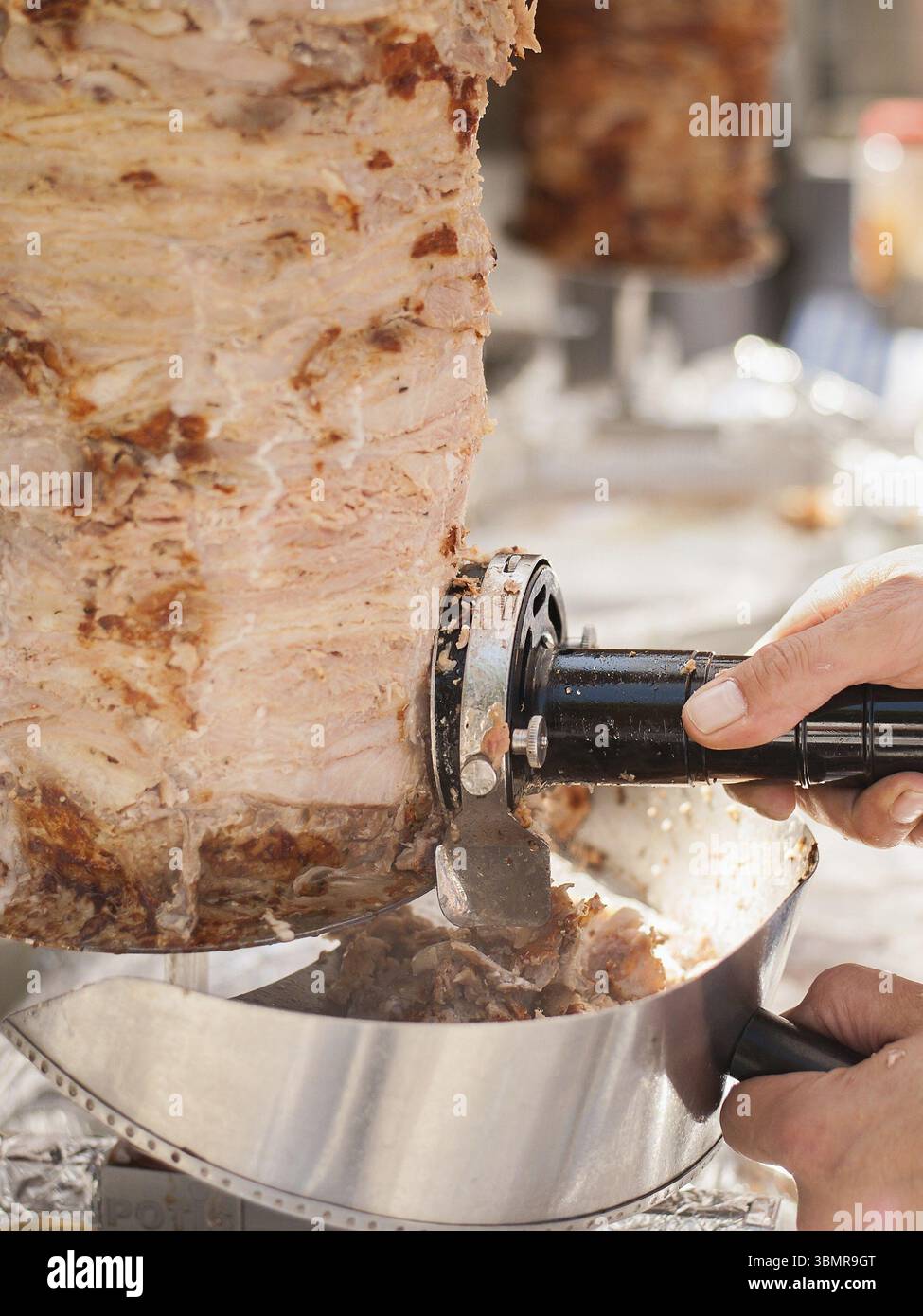 Hands of the Cook that with electric knife cut the doner kebab. The ...