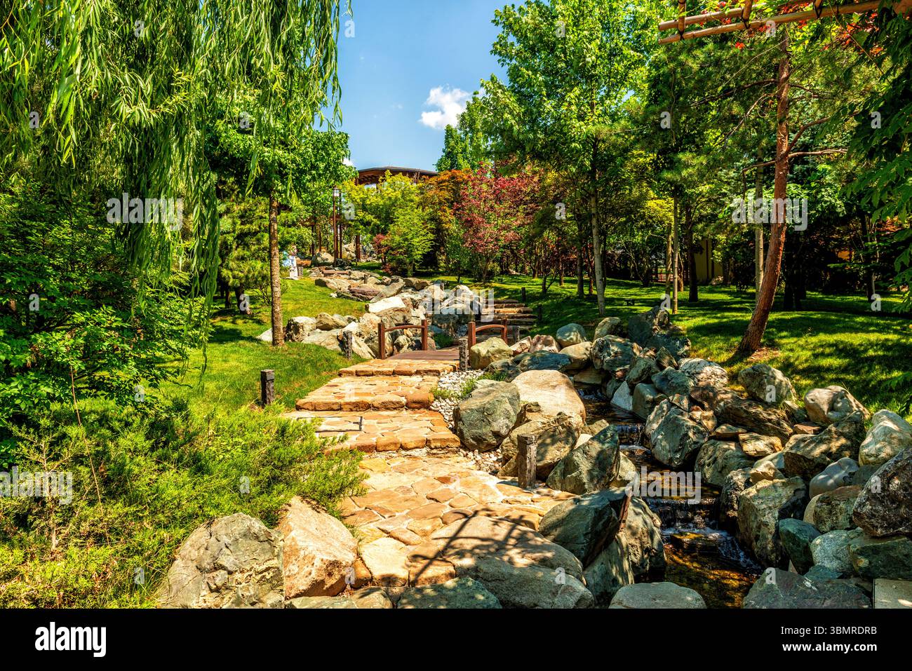 Park landscape with a pedestrian path and a man -made stream in a ...