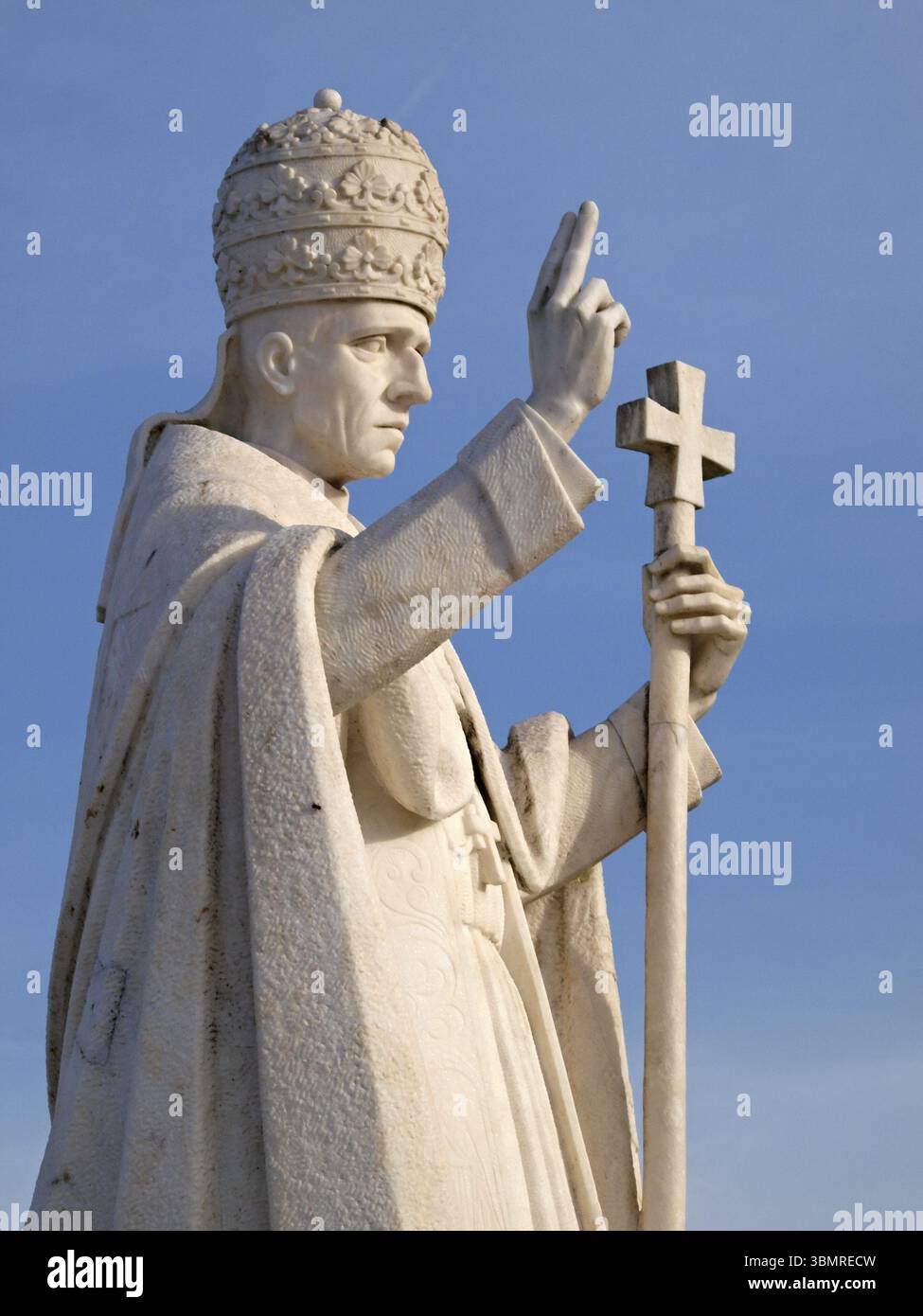 Marble statue of Pope John Paul II holding a cross and blessing, with a ...