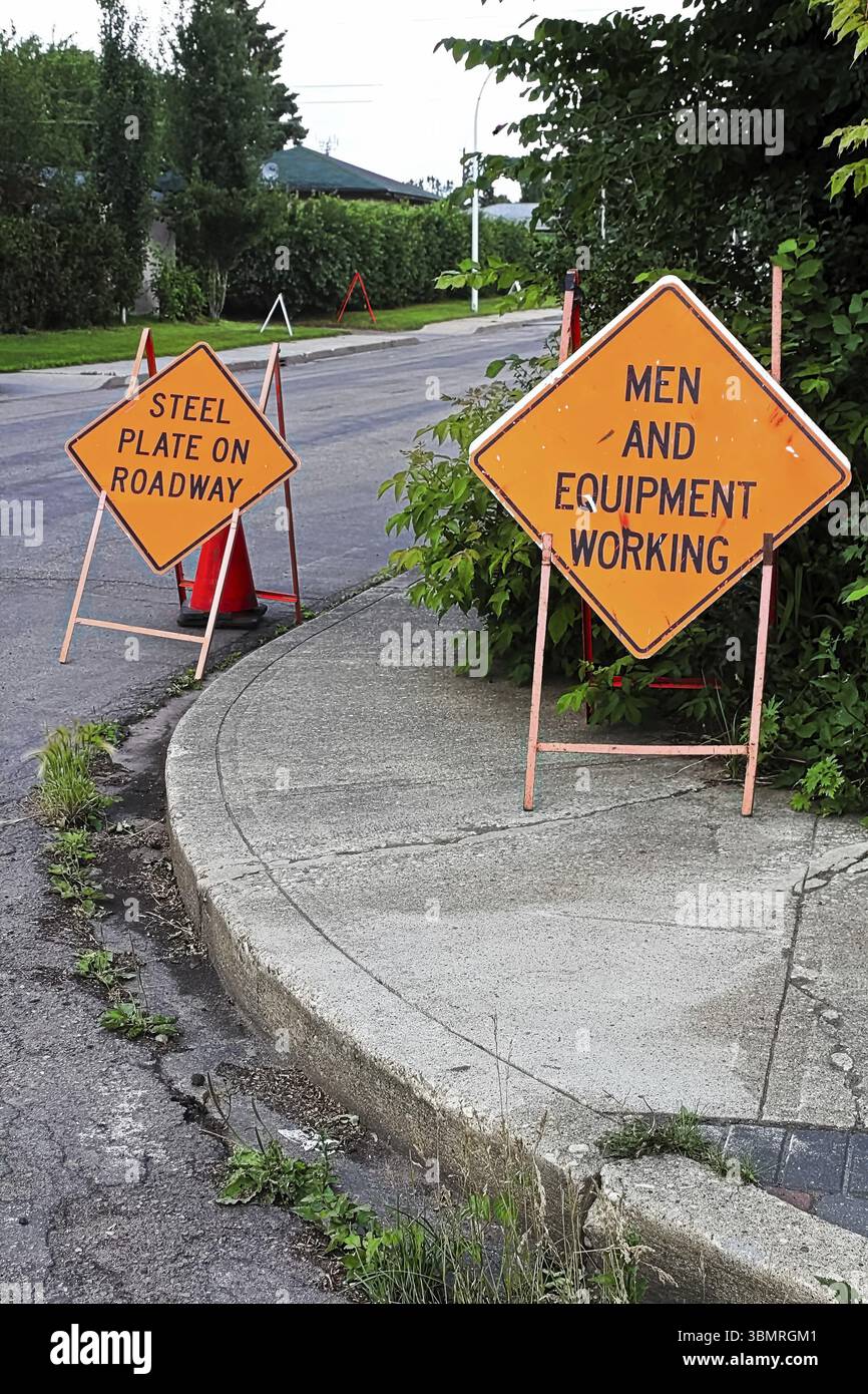 Orange men and equipment working construction sign Stock Photo - Alamy