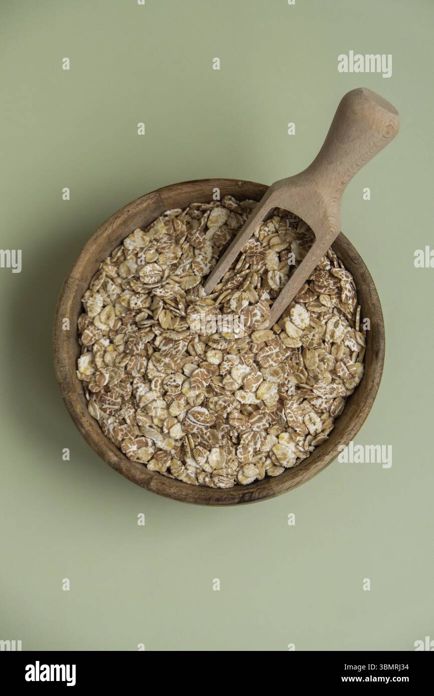 Raw oatmeal porridge in green background copy space. Whole spelt grain ...