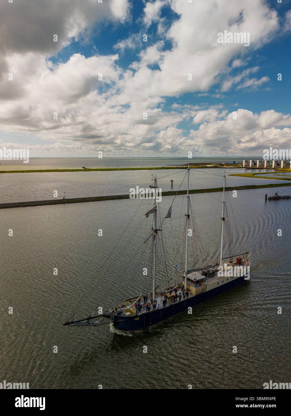 A majestic sailing ship glides across calm waters under a partly cloudy ...