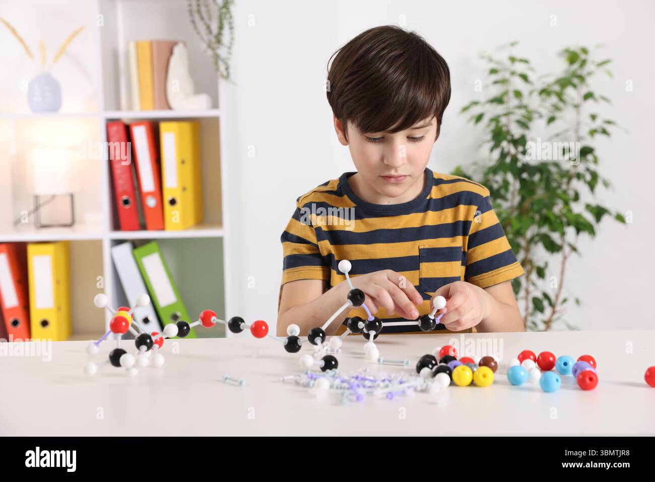 Boy making DNA structure model at desk indoors. Space for text Stock ...