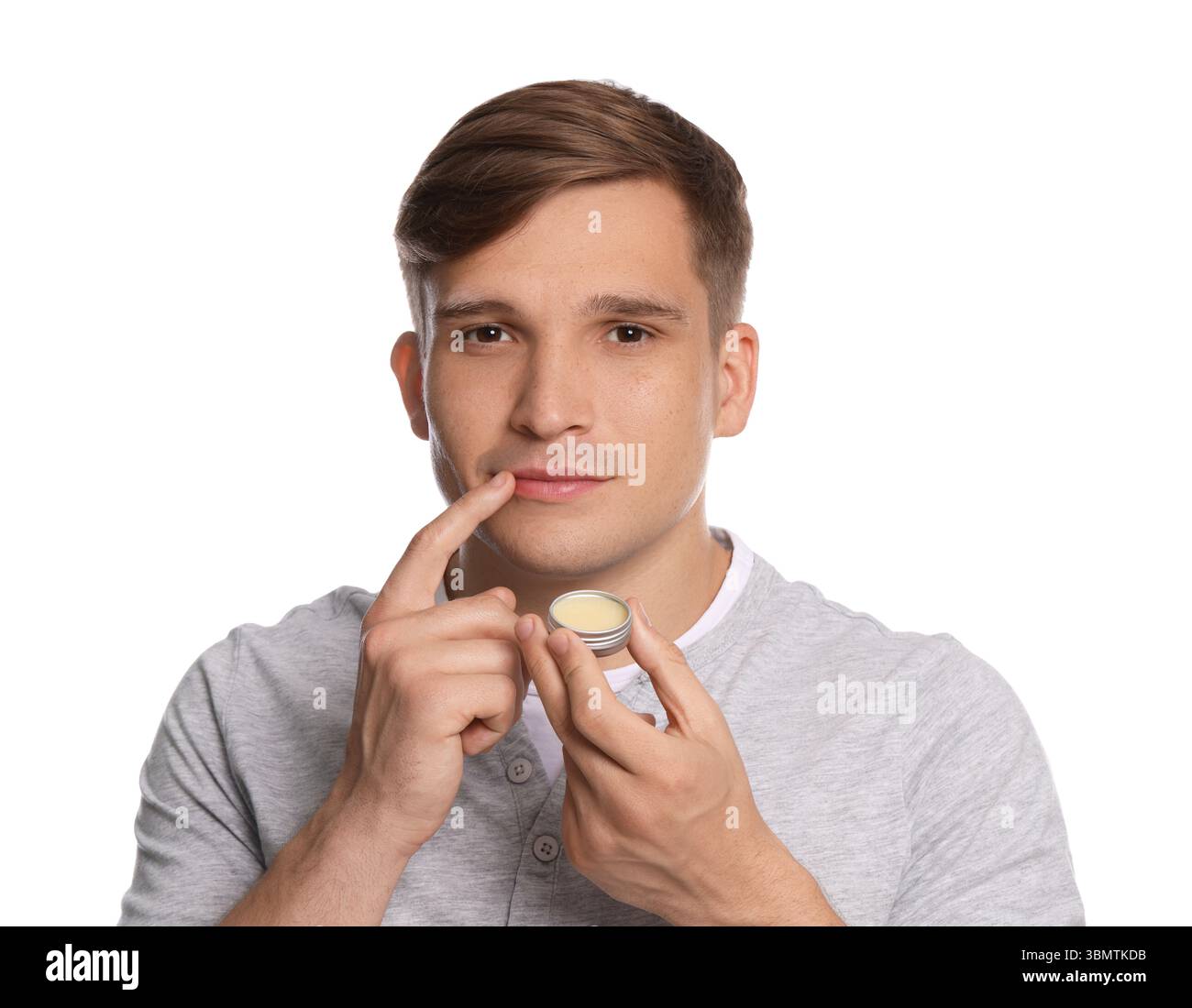 Young man applying lip balm onto his lips on white background Stock ...