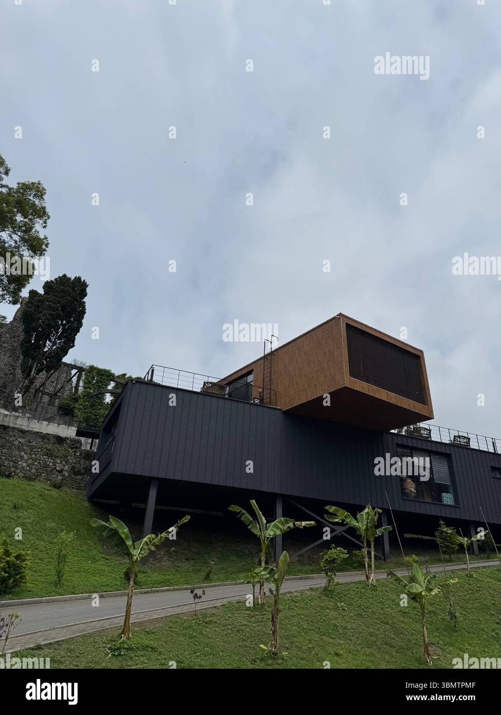 The image shows a modern elevated building constructed on metal stilts ...