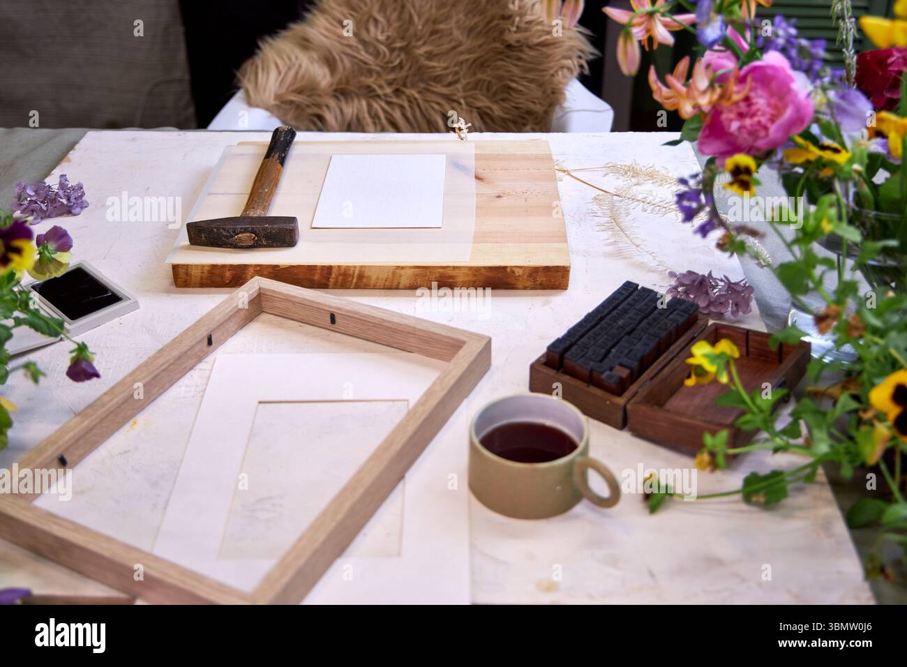 Top view of creative botanical printmaking setup with hammer, flowers ...