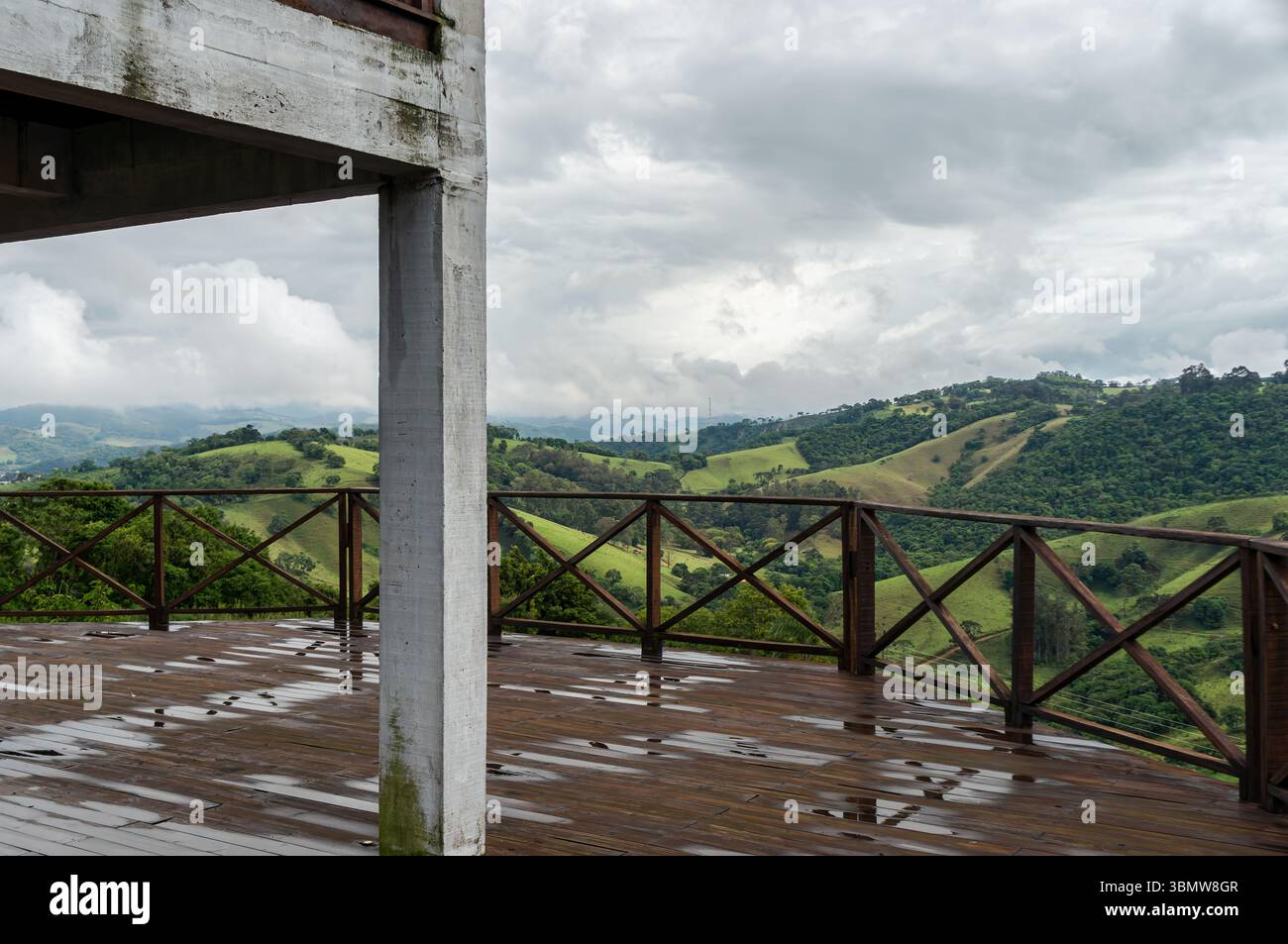 Wet wooden observation deck with rustic railing overlooking lush green ...