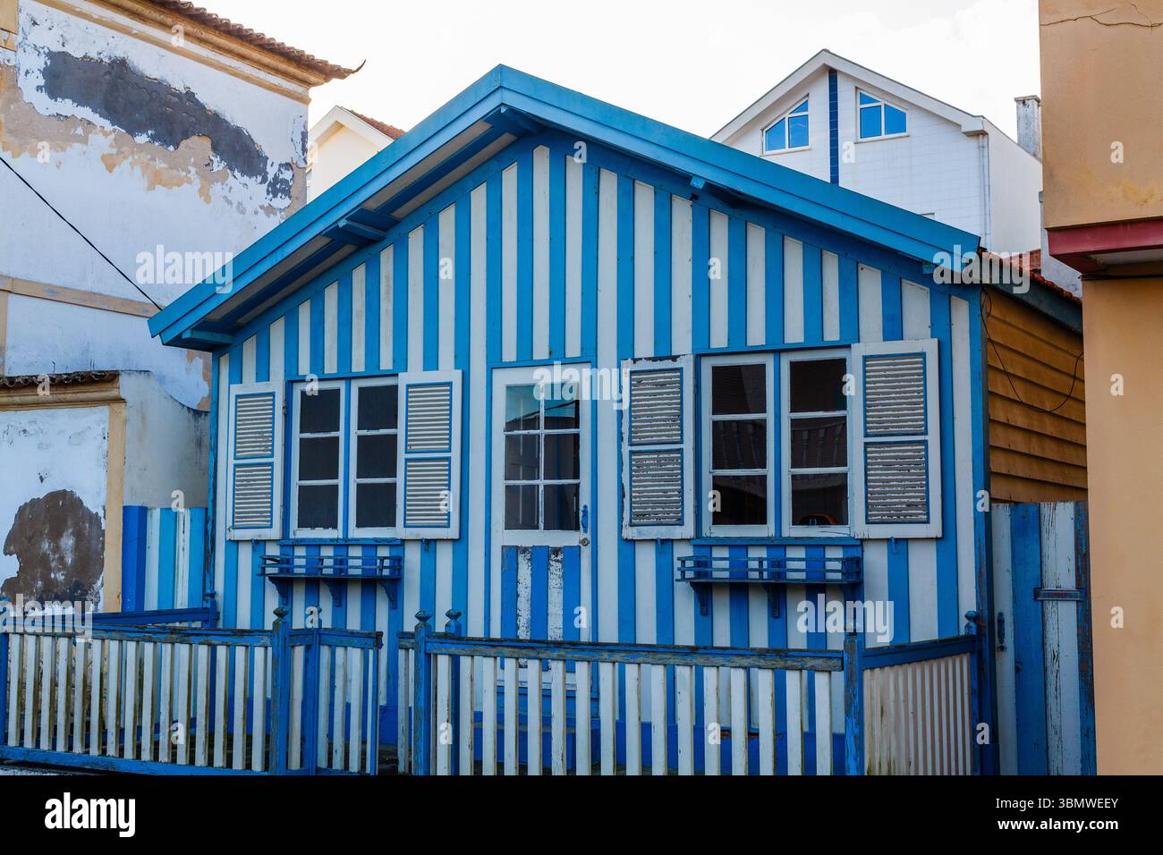 A quaint, blue and white striped wooden house with a white picket fence ...