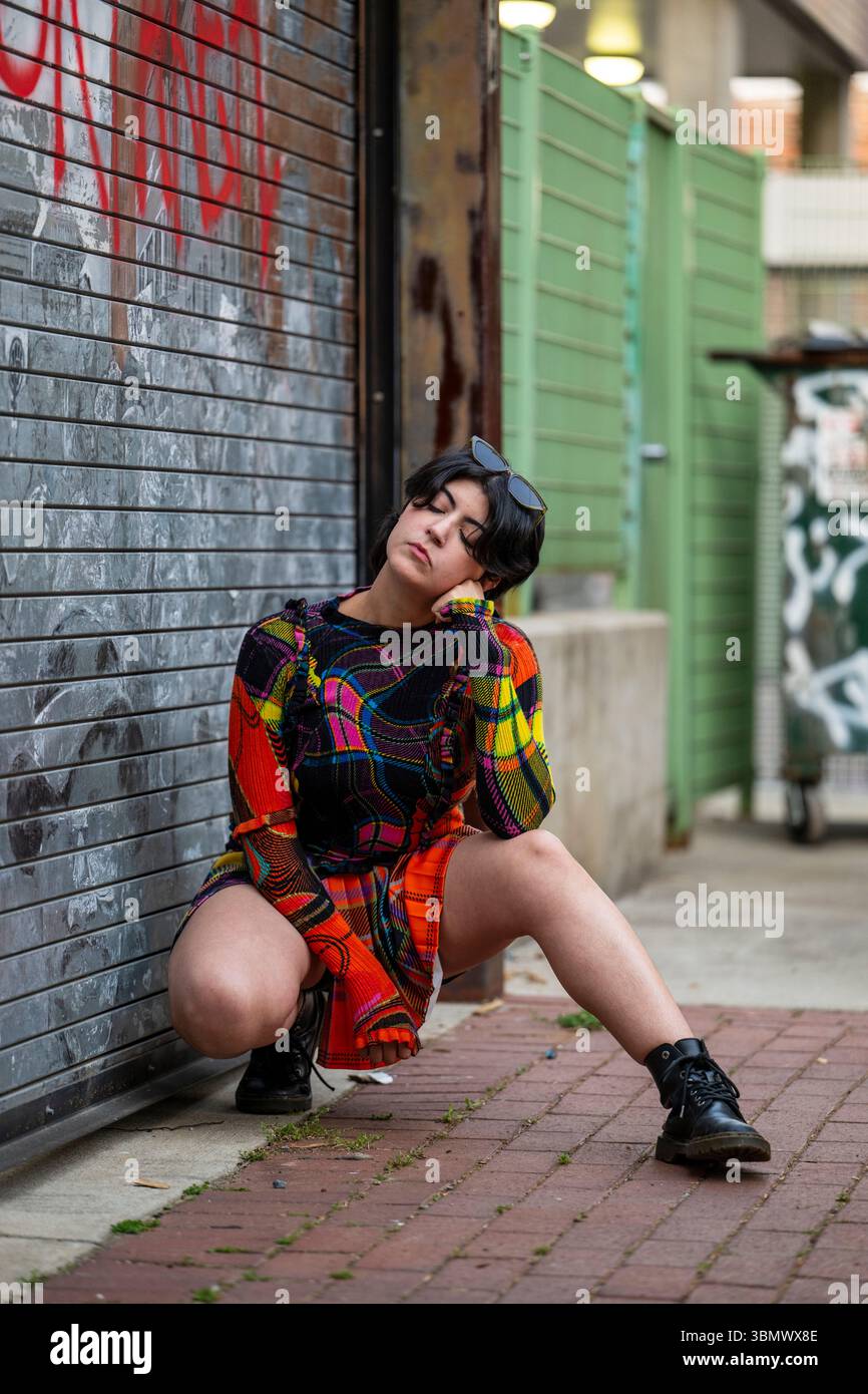 A young woman poses near graffiti-painted gates Stock Photo - Alamy