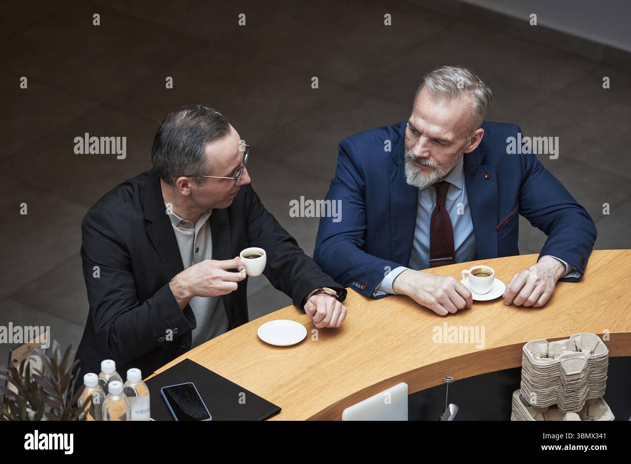 Two business professionals sitting at office cafeteria counter ...