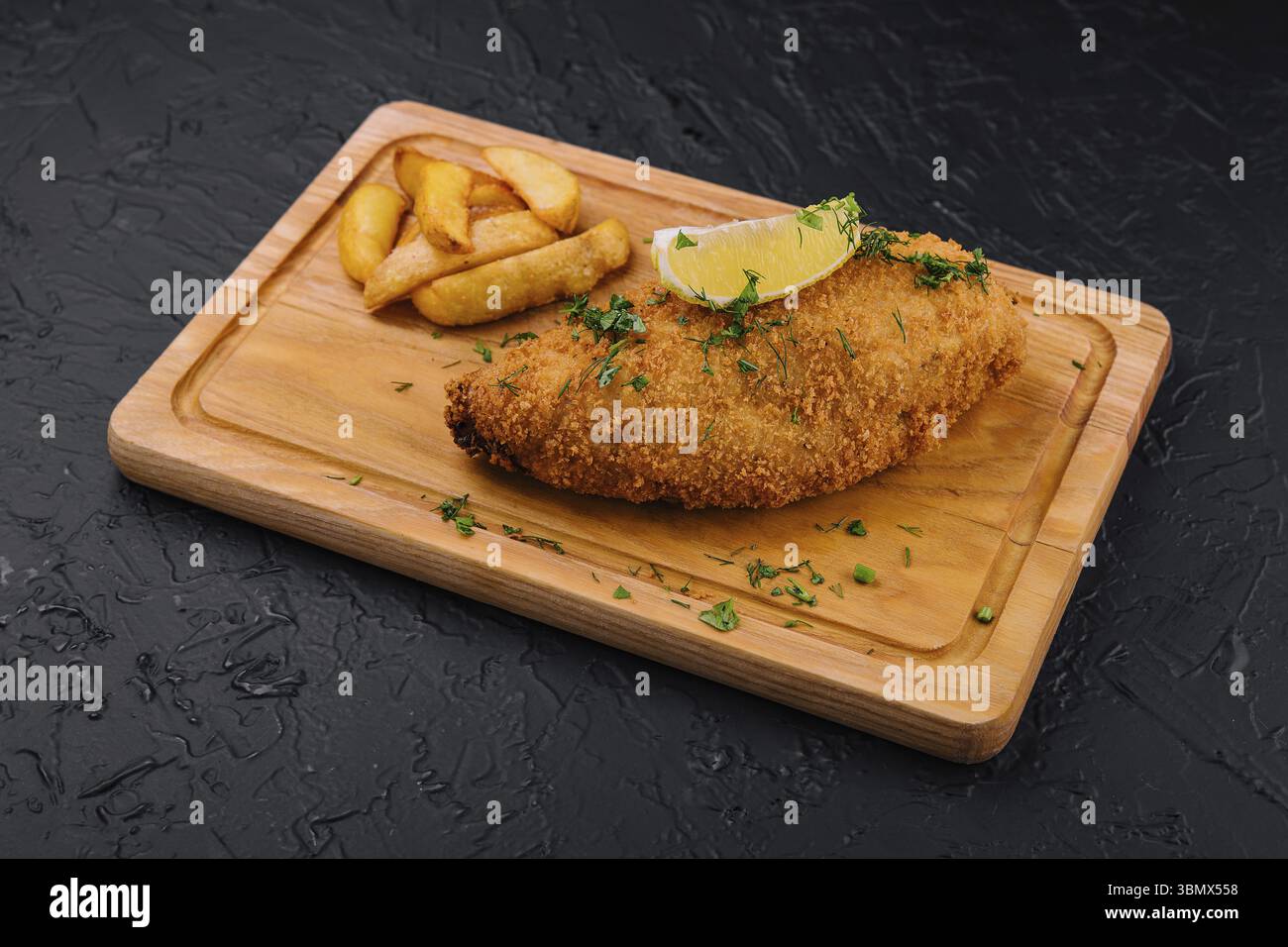 food still-life, Breaded schnitzel with french fries on a cutting board ...