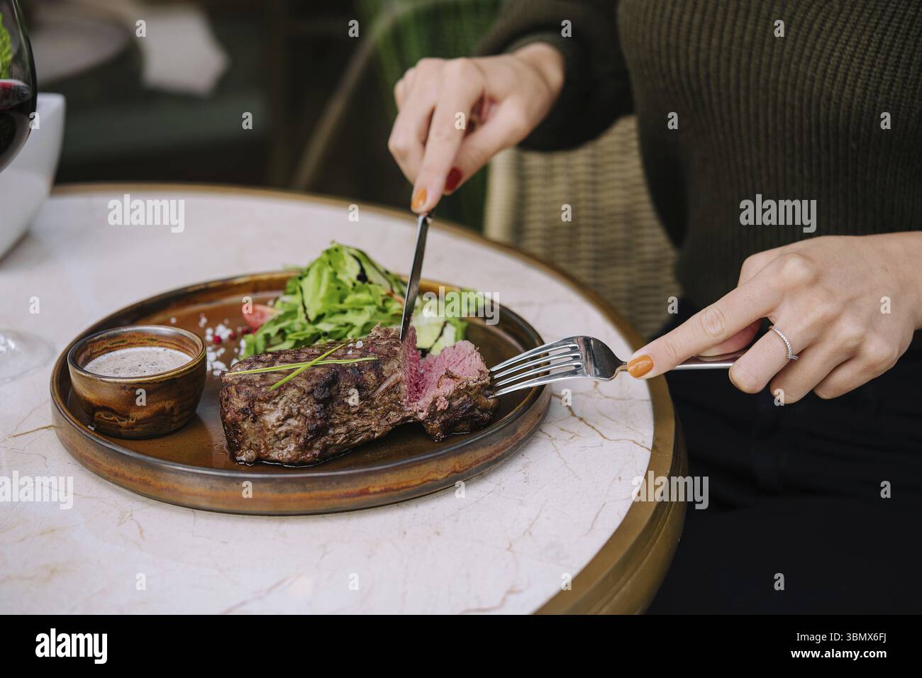 food still-life, Female hands in a restaurant at the table cut beef ...