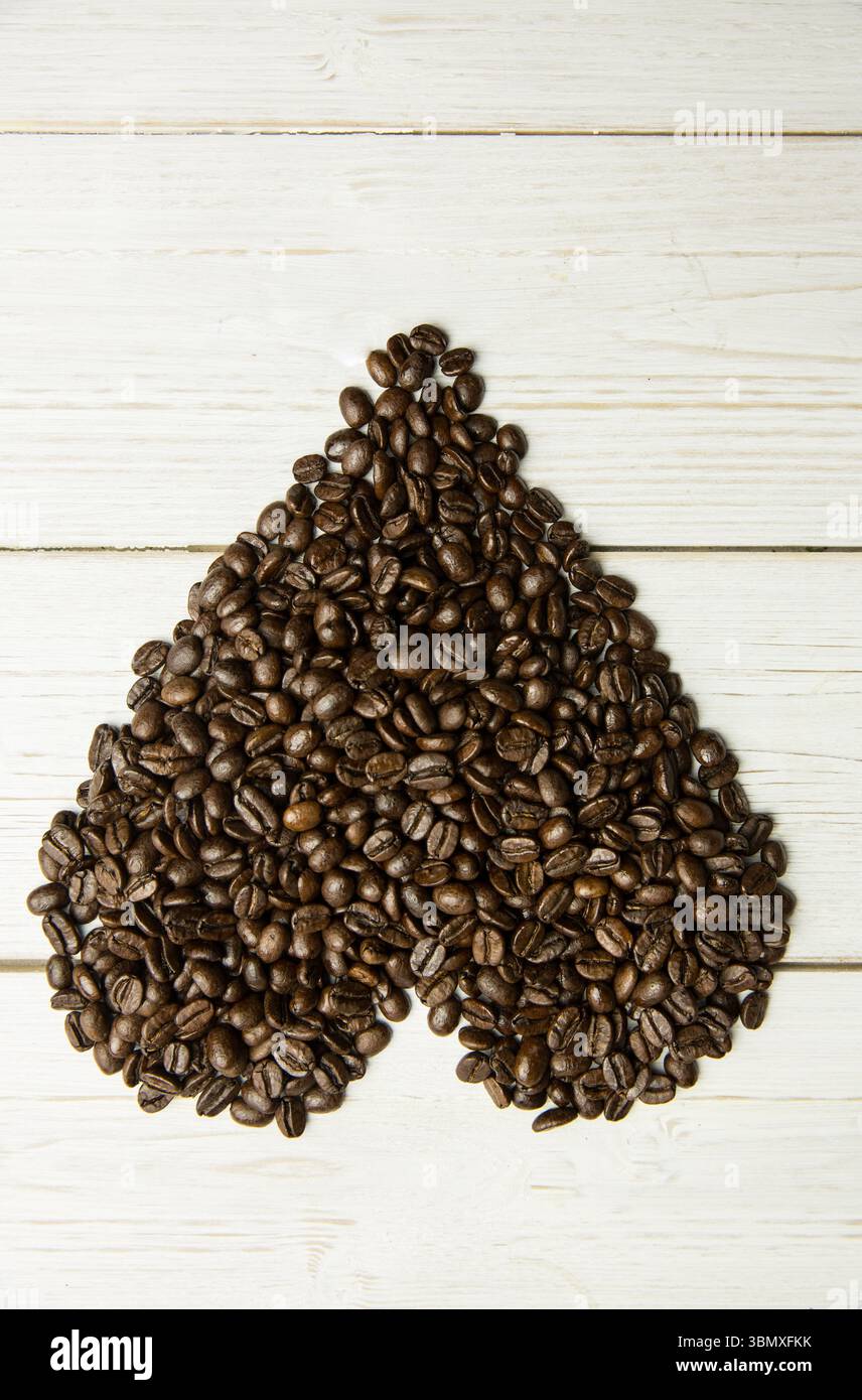 Heart-shaped coffee beans are forming on white painted wooden plank ...
