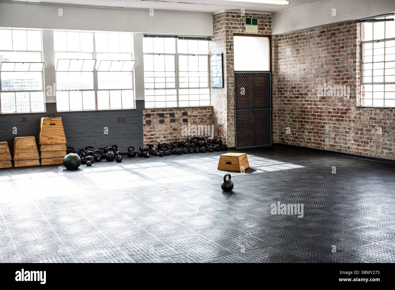 Single black kettlebell is sitting on rubber floor inside brick gym ...