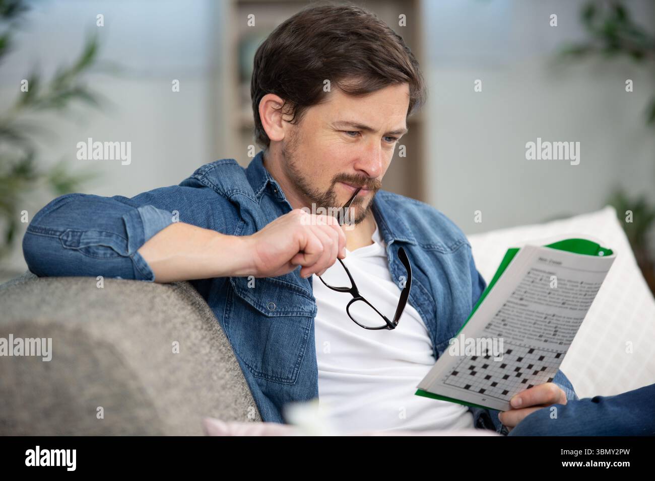 young man sitting doing a crossword puzzle looking thoughtfully Stock ...