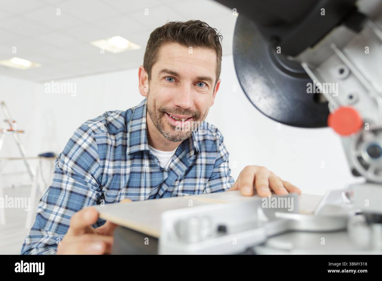 handsome man carpenter using a circular saw Stock Photo - Alamy