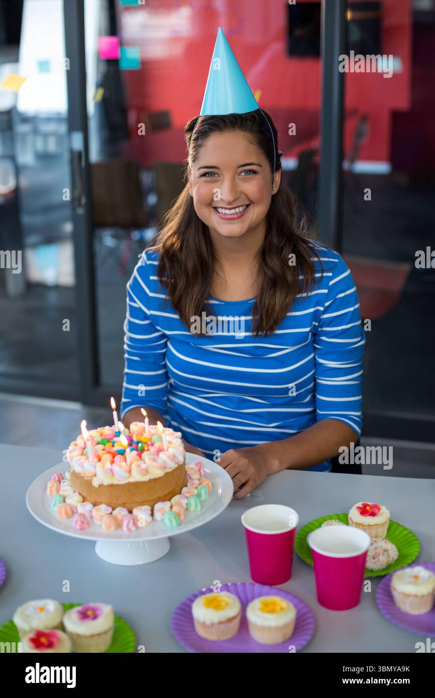 Adult woman blowing out candles on birthday cake at office meeting room ...