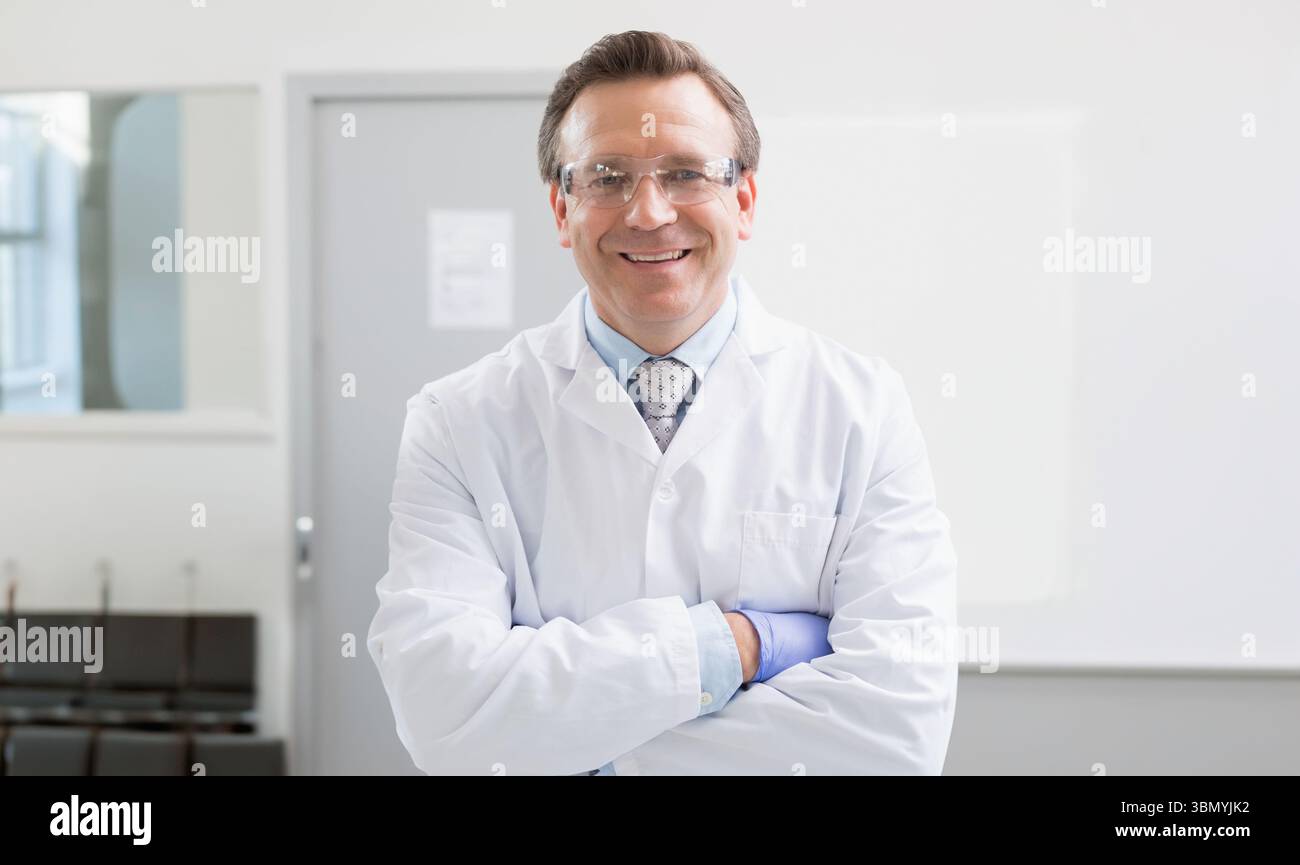Male doctor standing arms crossed in clinical room wearing lab coat ...