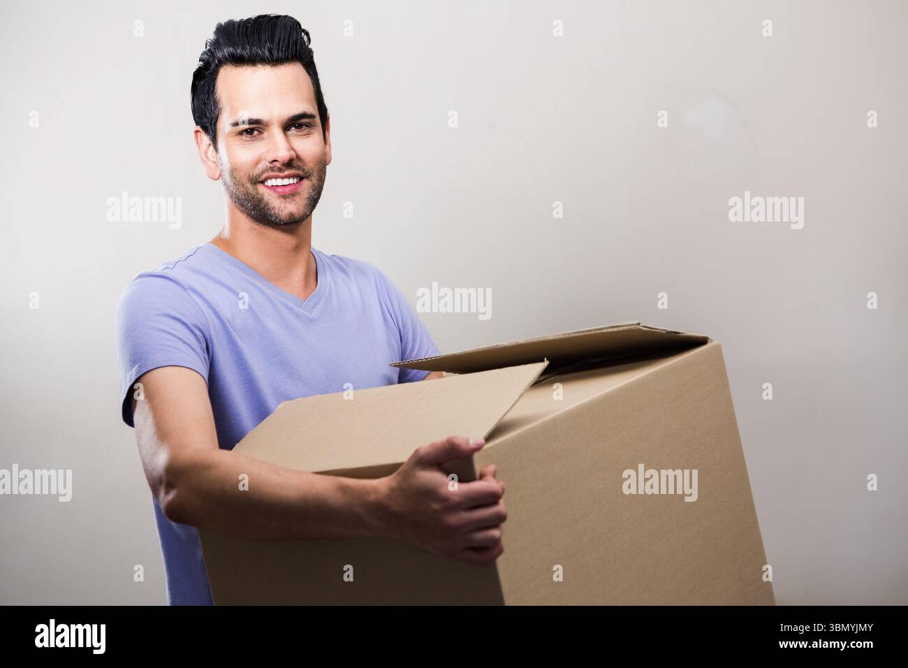 Man holding large open-top cardboard box while standing in room with ...