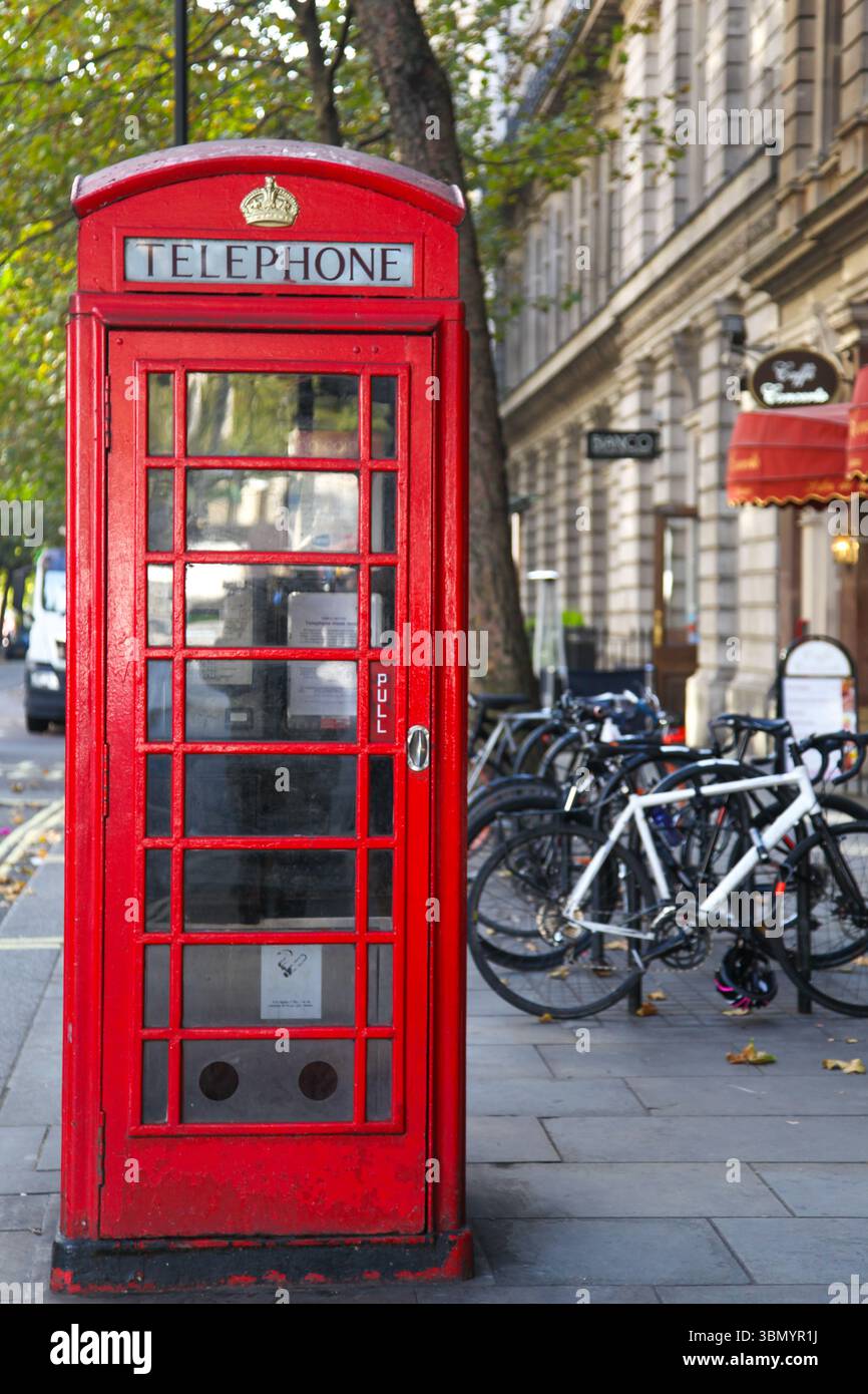 Classic red British phone booth on a quiet London street in October. A ...